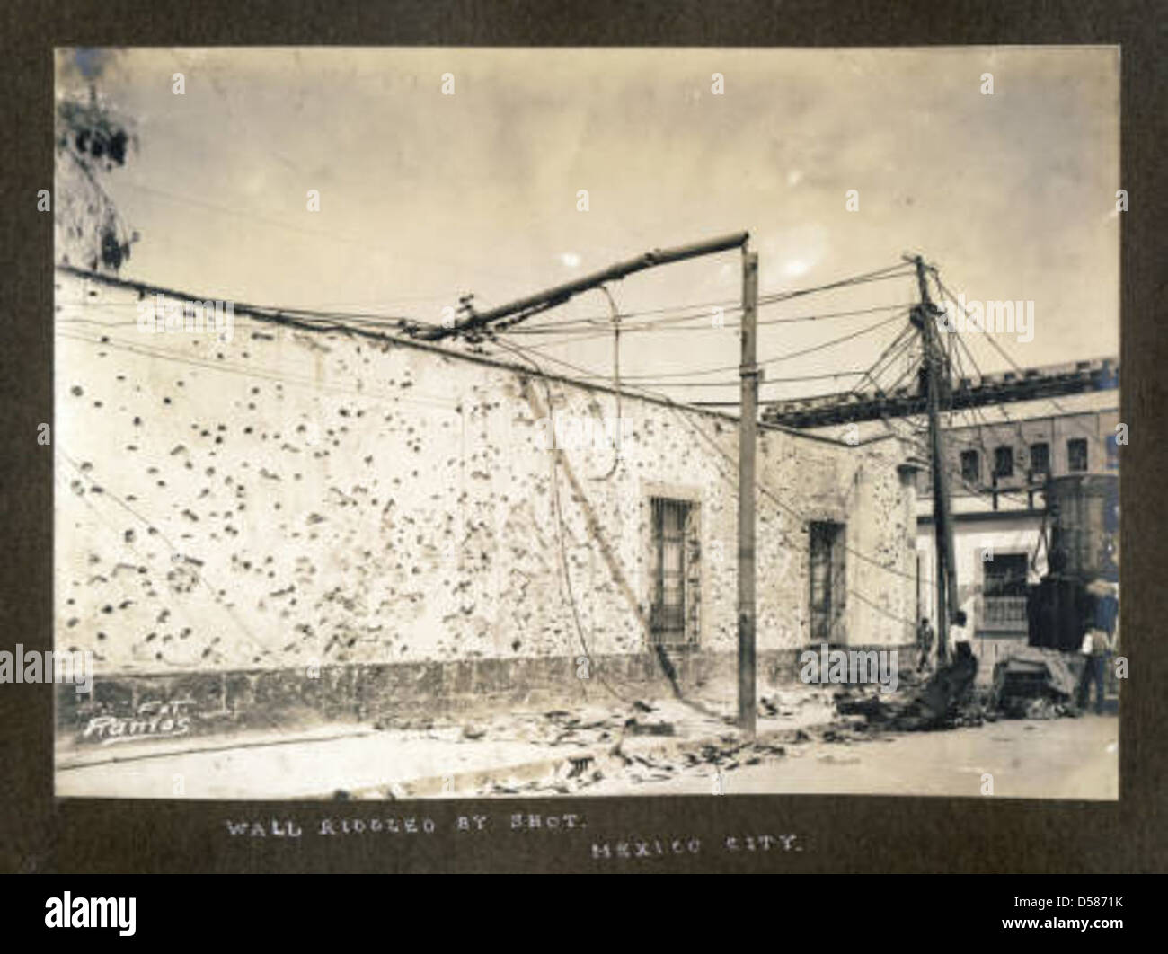 This image depicts a wall in Mexico City marked by bullet holes ...