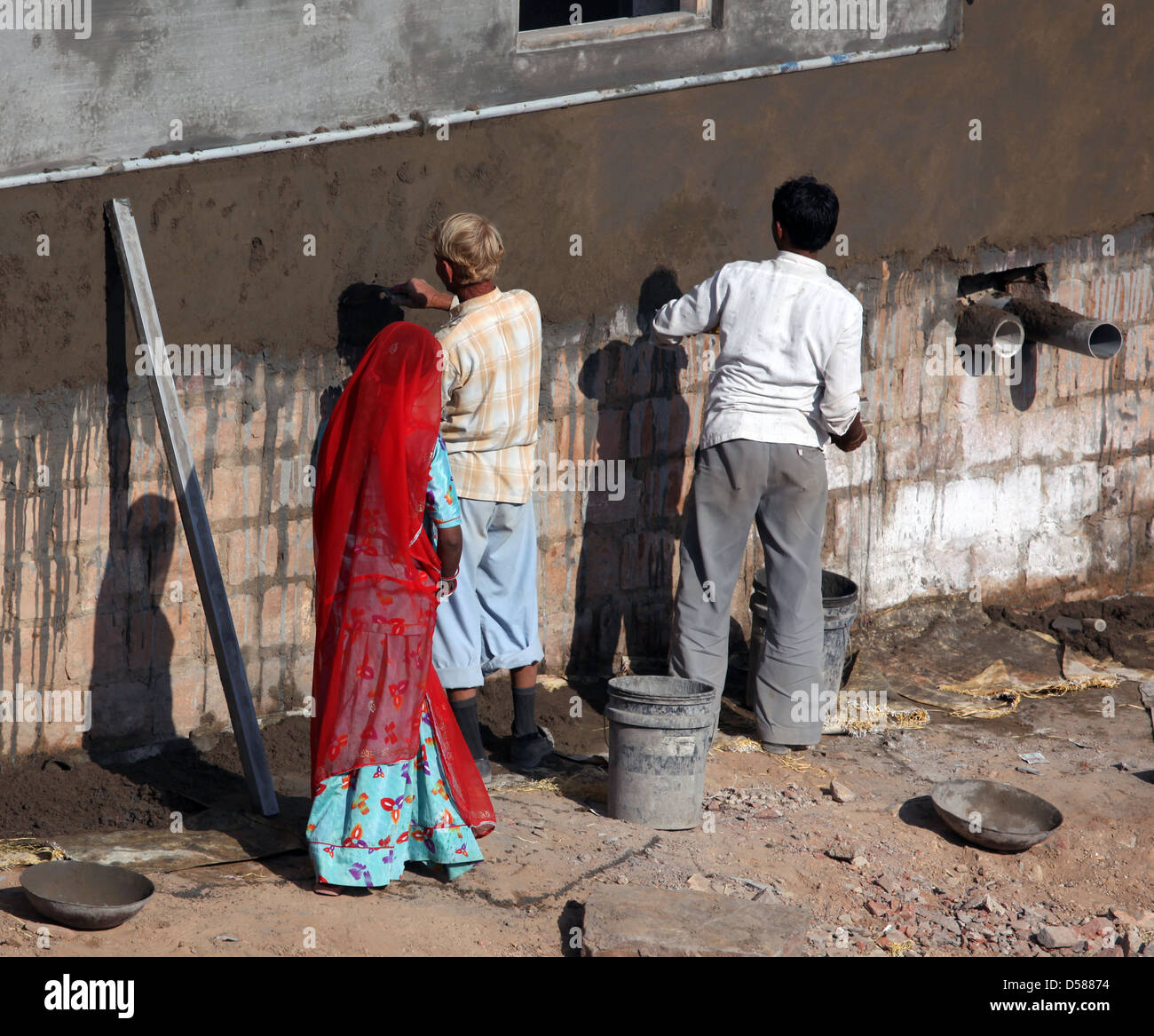 Building work in Bhap, Rajasthan, India, overlooked by lady in a ...