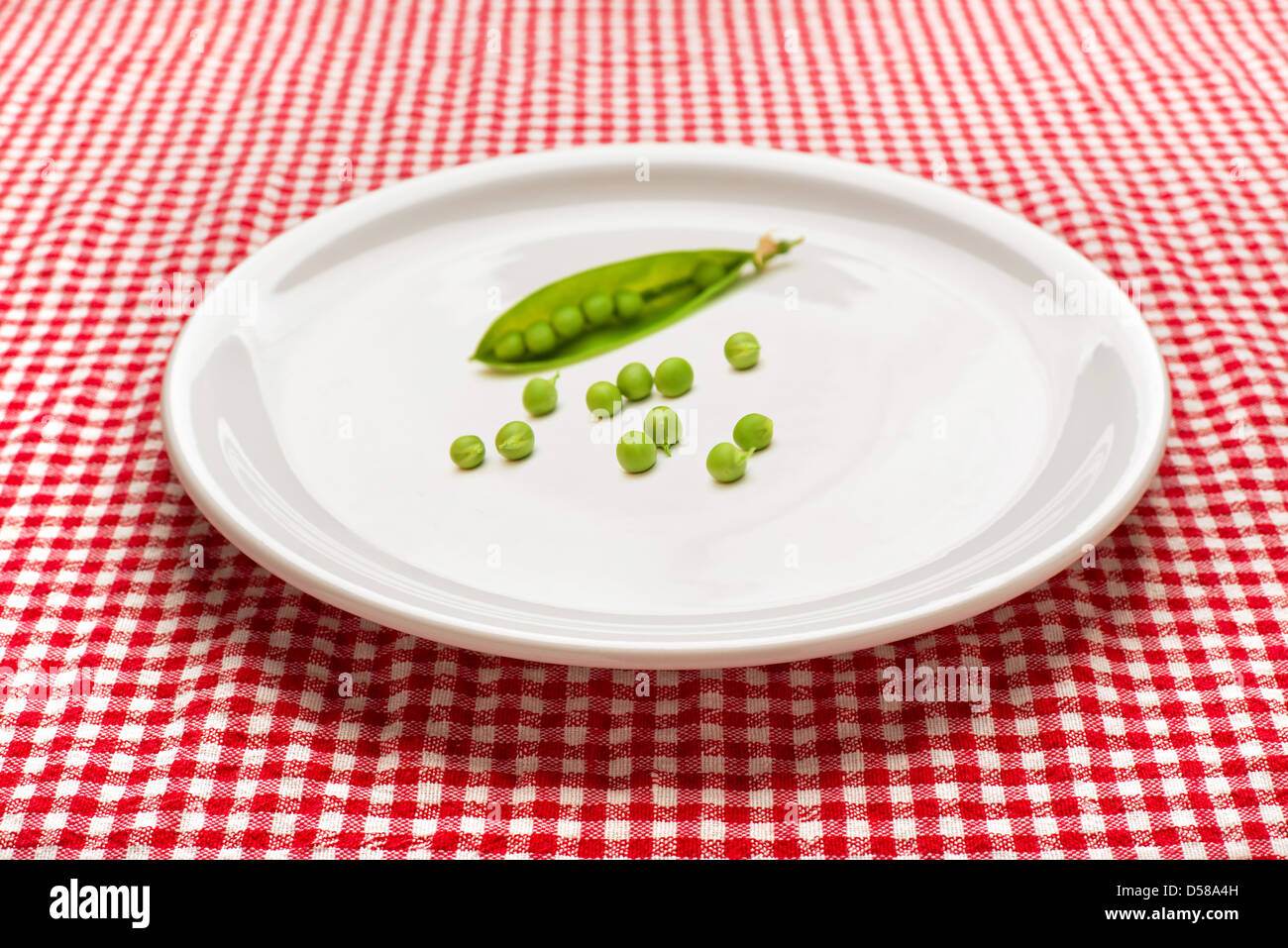 Raw peas on white ceramic plate served on kitchen table. Dieting and ...