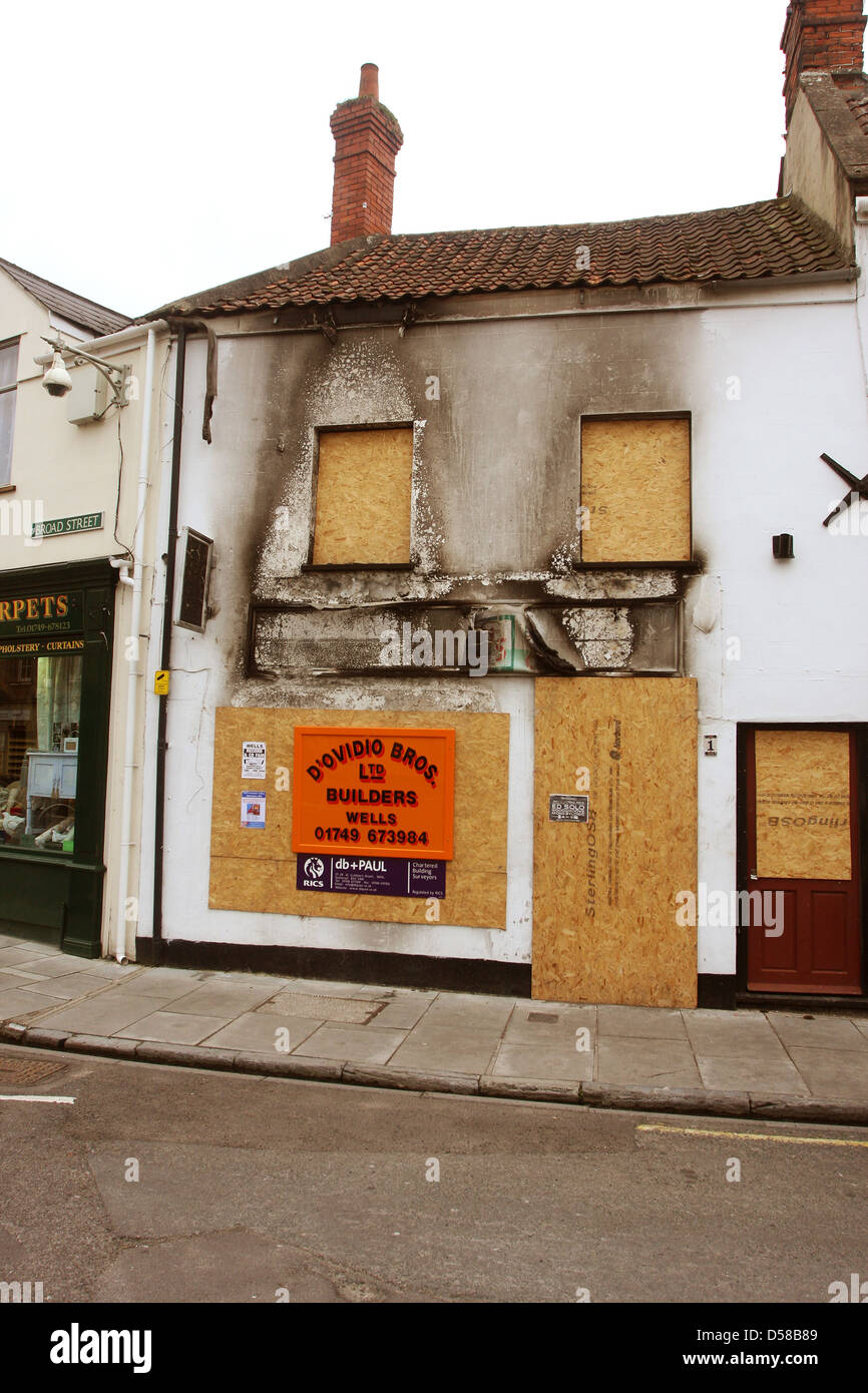 Boarded up fire damaged shop in the City of Wells in Somerset, at the ...