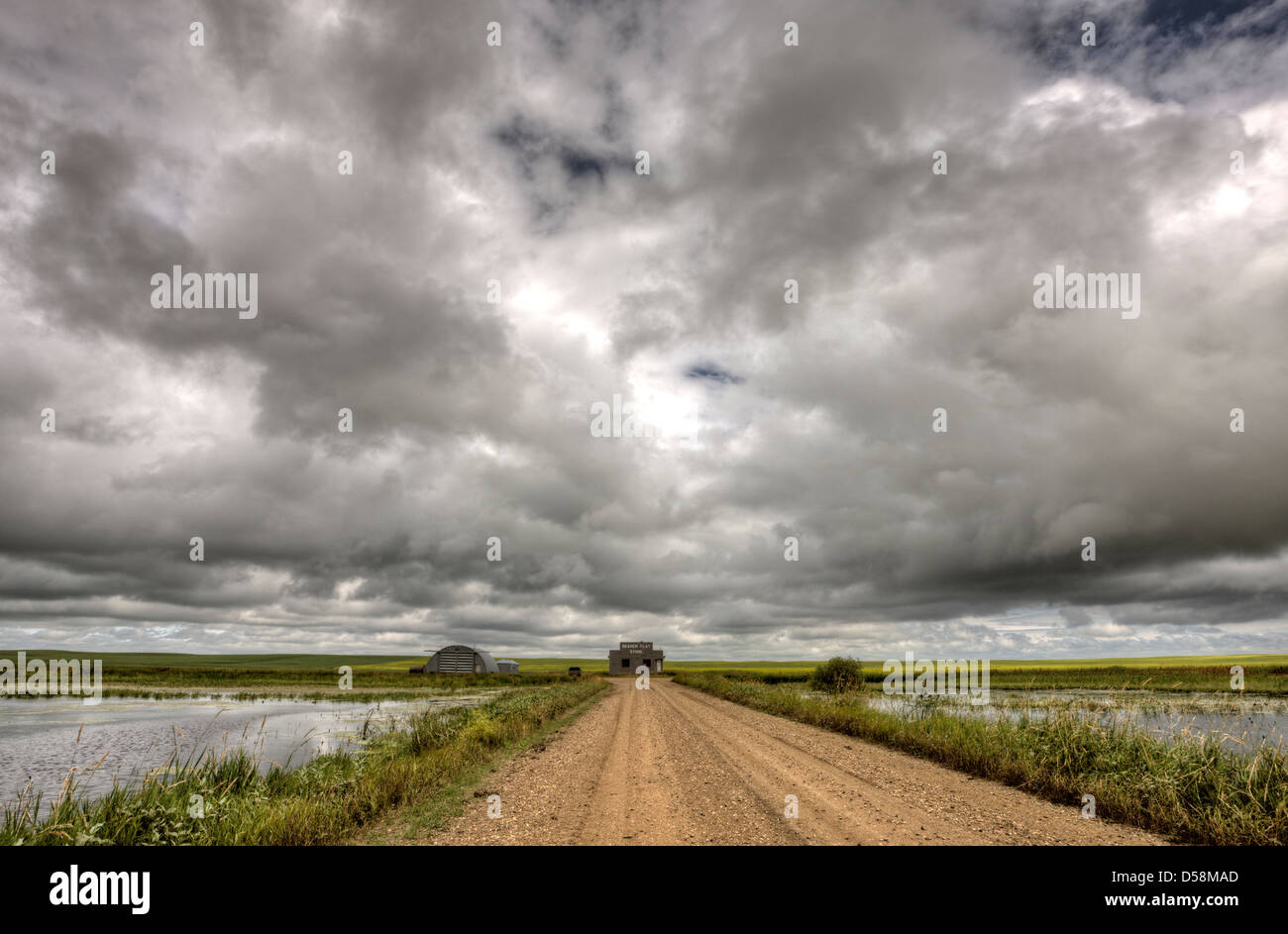 Storm Clouds Saskatchewan gravel grid road and pond Stock Photo - Alamy