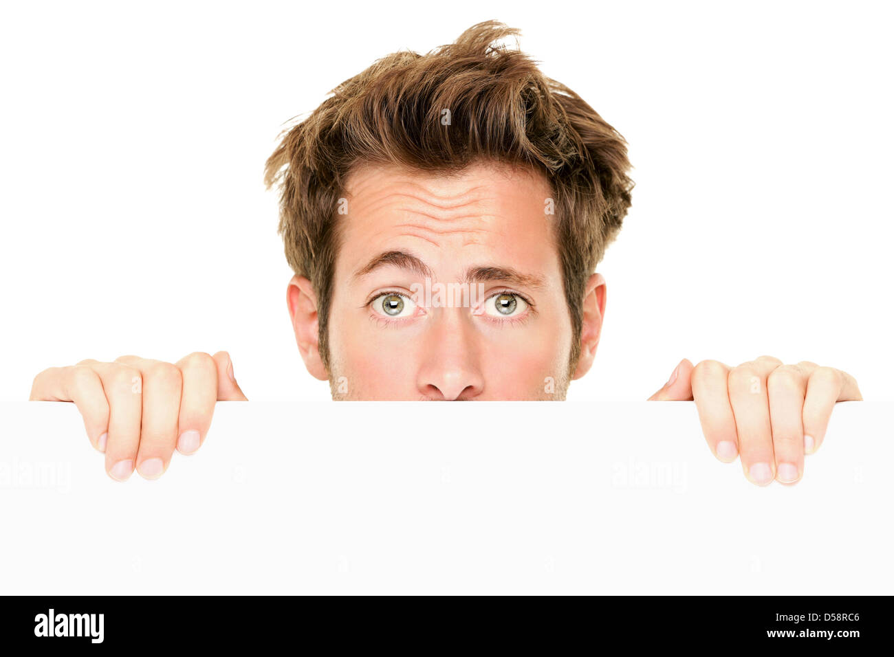 Portrait of surprised Caucasian young man peeking over blank sign ...