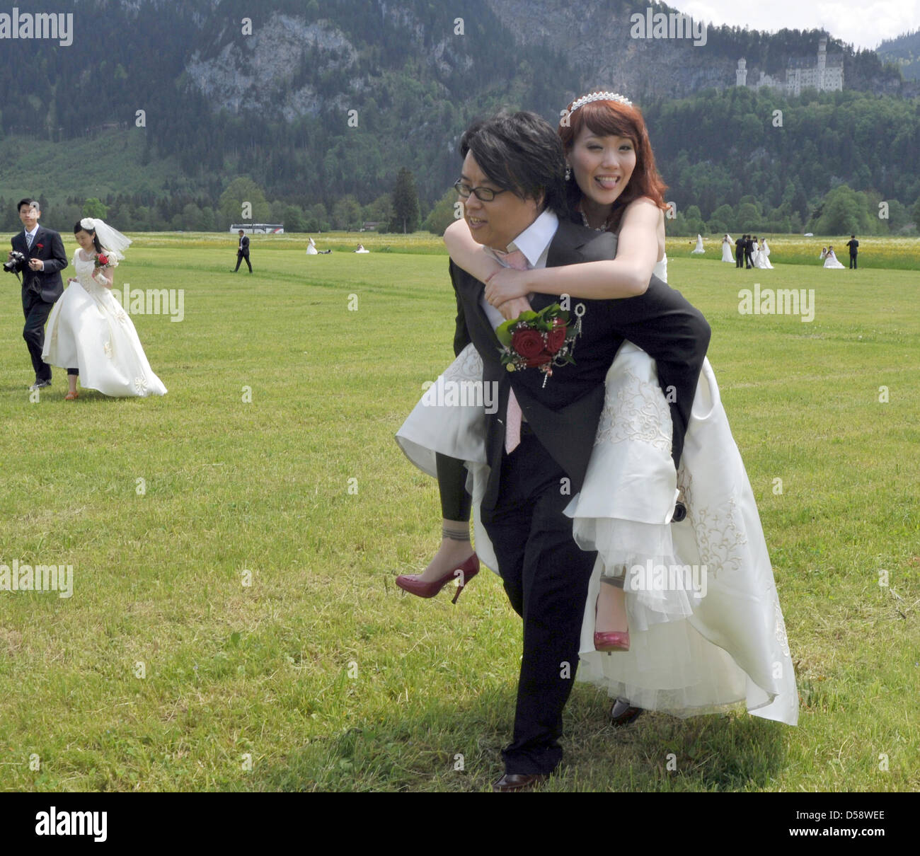 A groom carries his bride in front of Neuschwanstein Castle in Fuessen ...