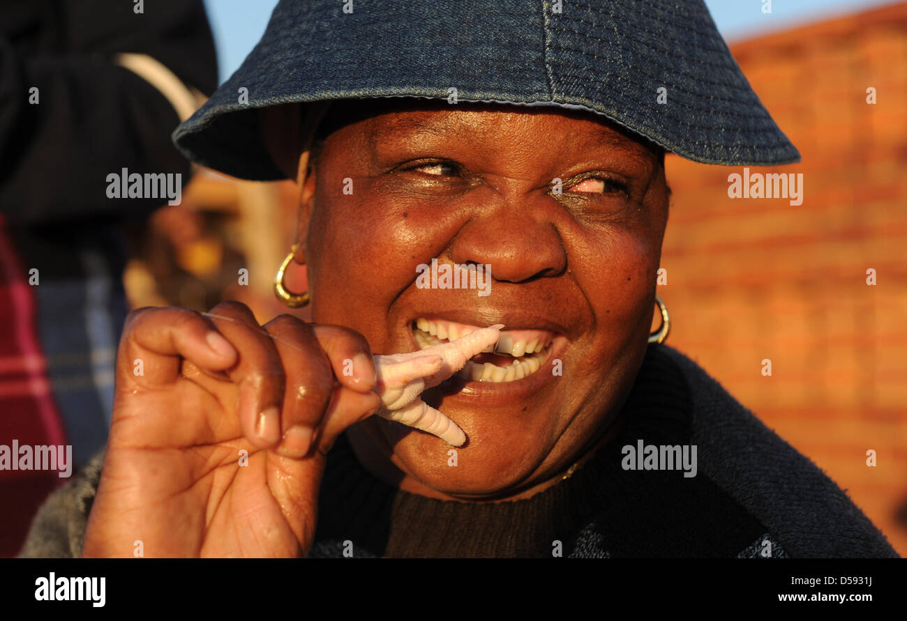 An African woman bites on a chicken leg in Atteridgeville near Pretoria ...