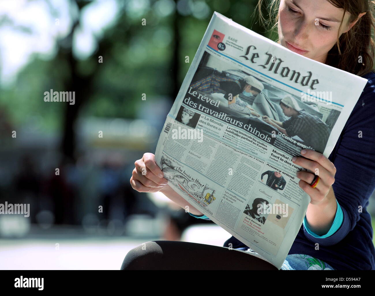 A woman reads an issue of French daily newspaper 'Le Monde' in ...