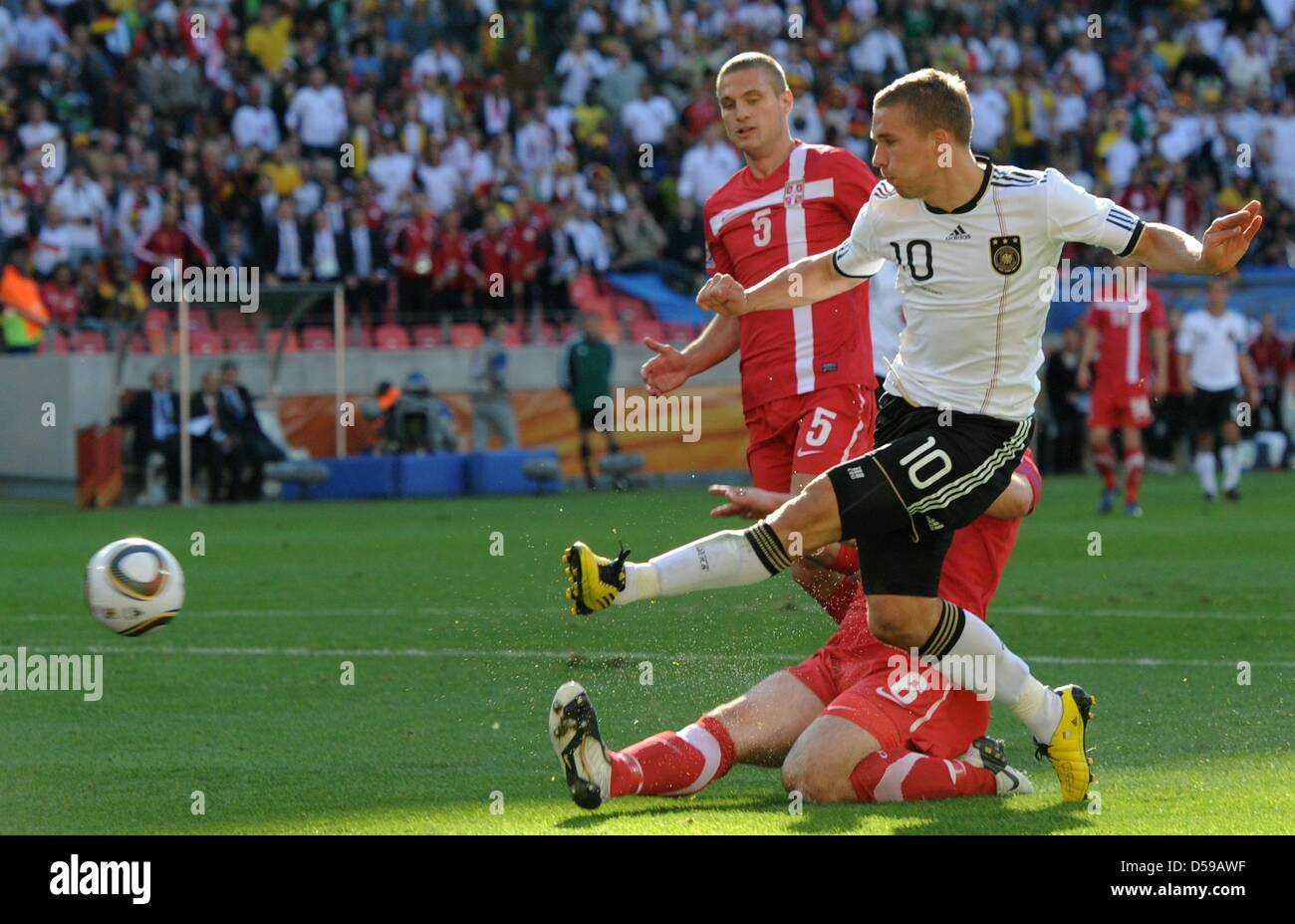 Germany's Lukas Podolski shoots past Serbia's Nemanja Vidic and ...