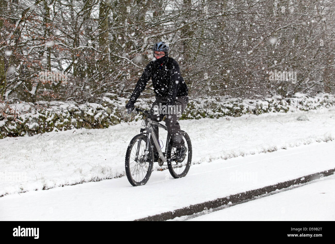 cyclist cycling in heavy snow during blizzard in Scotland in the UK ...