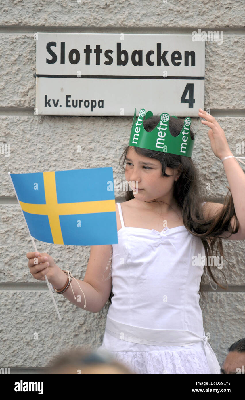 A little girl, holding the Swedish flag in her hand and wearing a crown ...