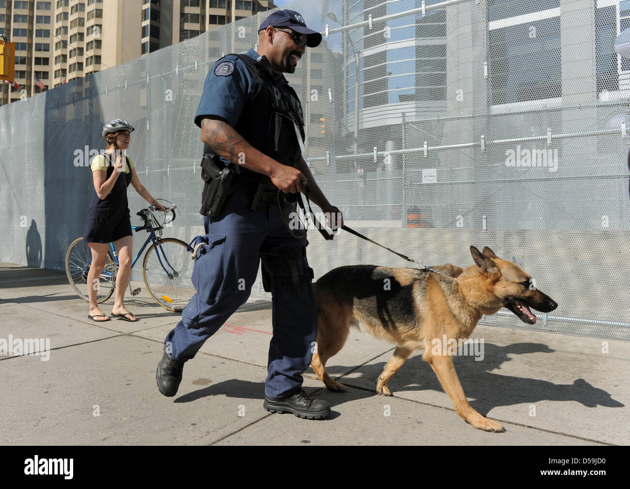A policeman with a dog in front of big crowd barriers in Toronto ...
