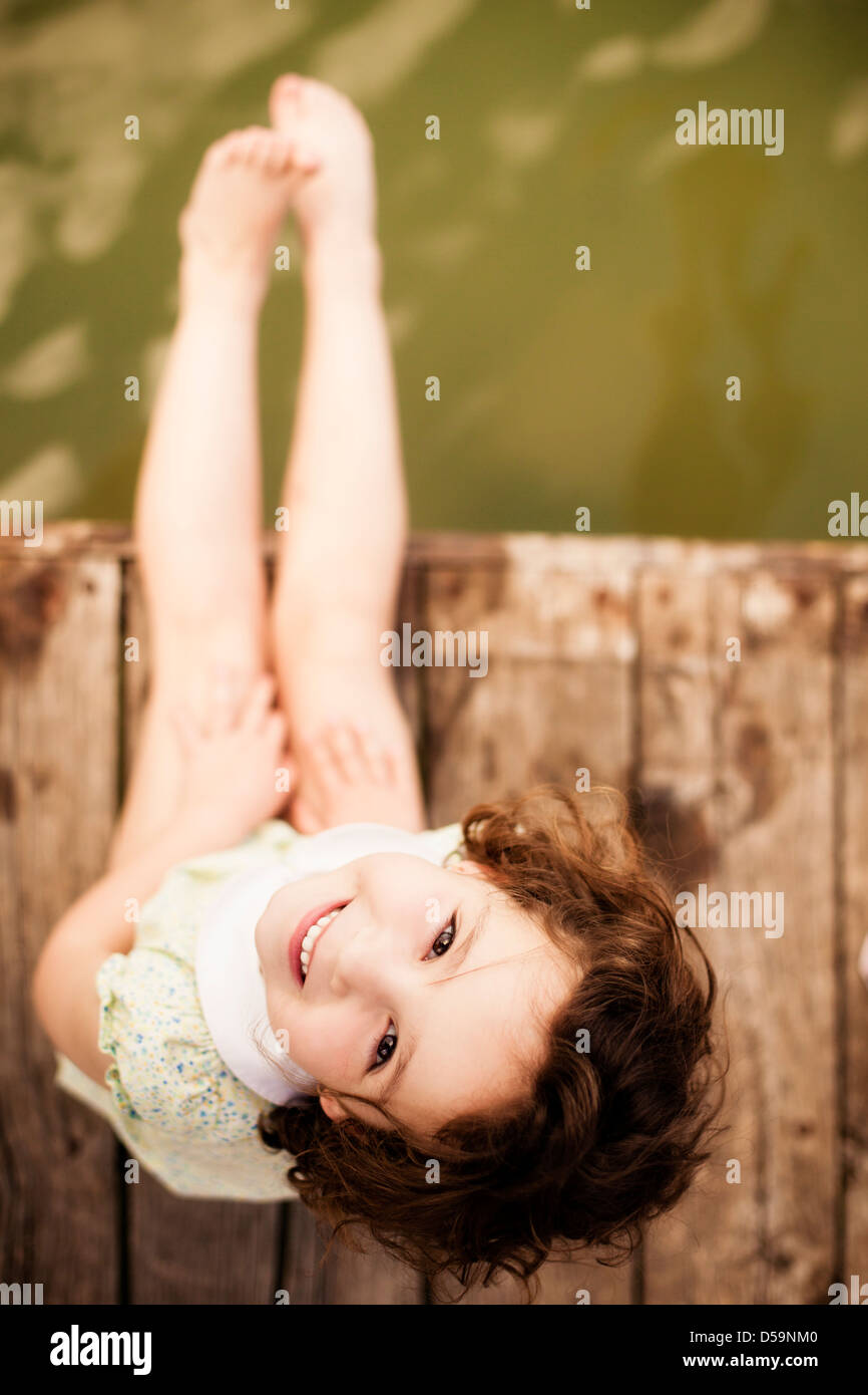 Pretty child sitting on wooden surface Stock Photo - Alamy