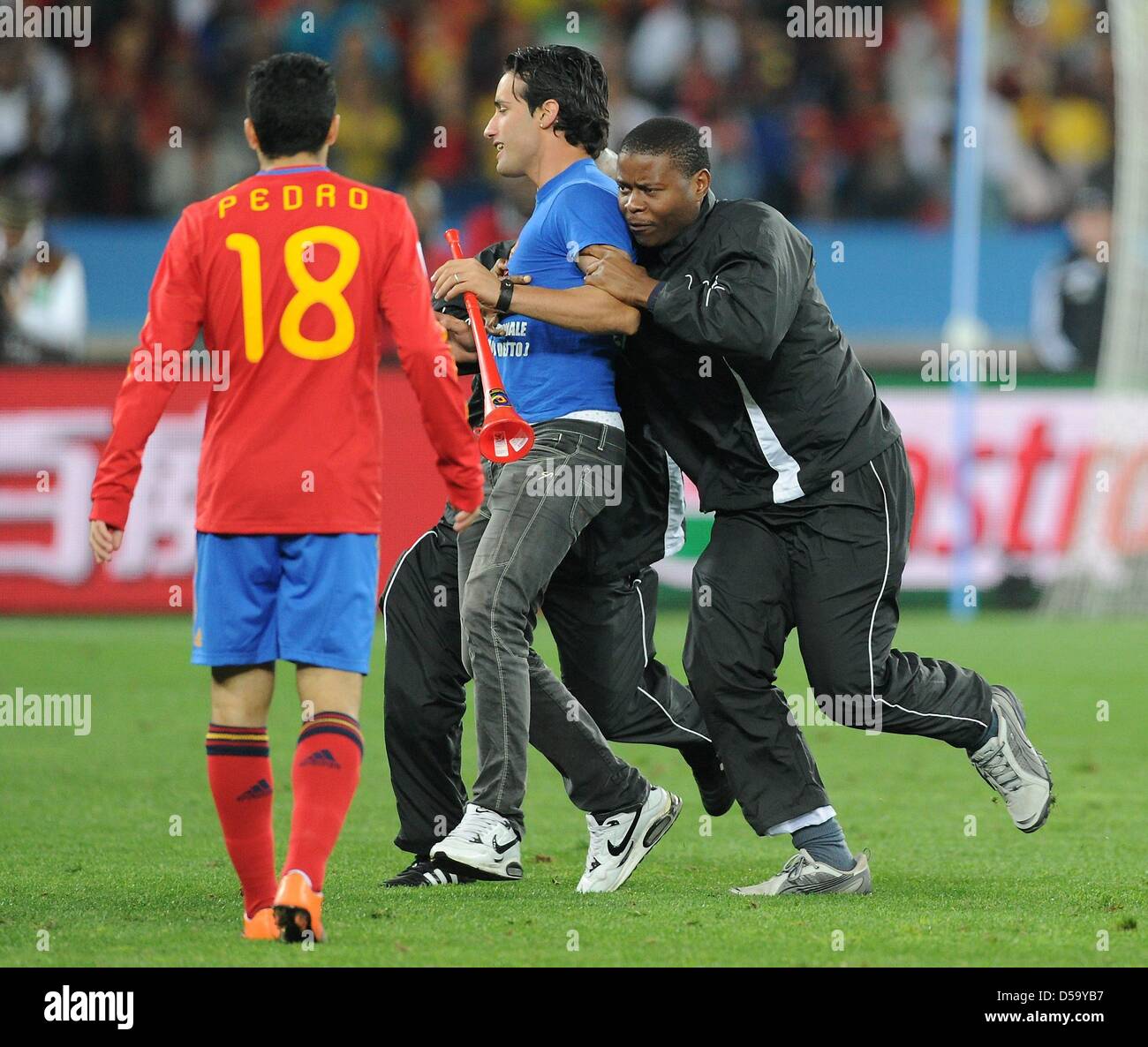 A runner is walked off the pitch past Spain's Pedro during the 2010 ...
