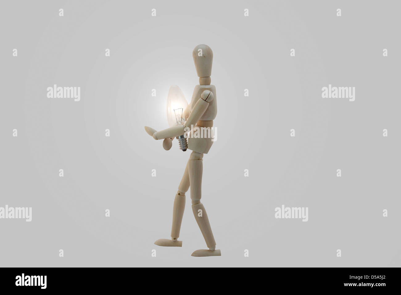 A Wooden Manikin Doll Holding An Illuminated Bulb Stock Photo - Alamy