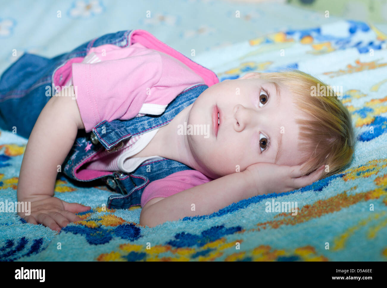the baby is lining on the bed with bright blue plaid with yellow flower ...