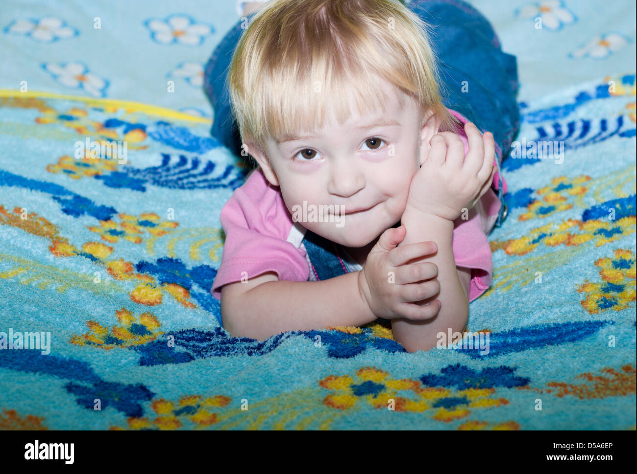 the baby is lining on the bed with bright blue plaid with yellow flower ...