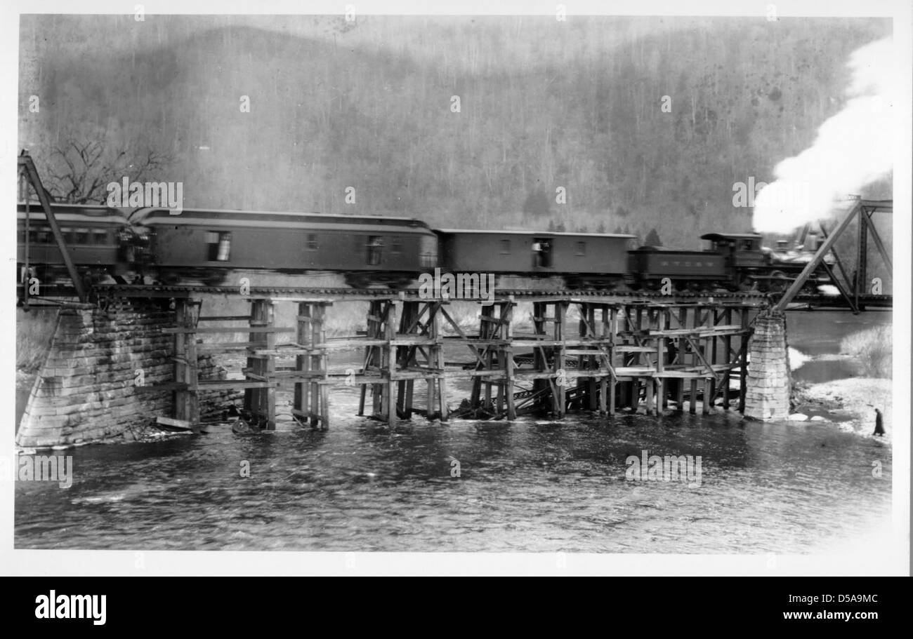 A photograph of a mixed train crossing a railroad bridge, showcasing ...