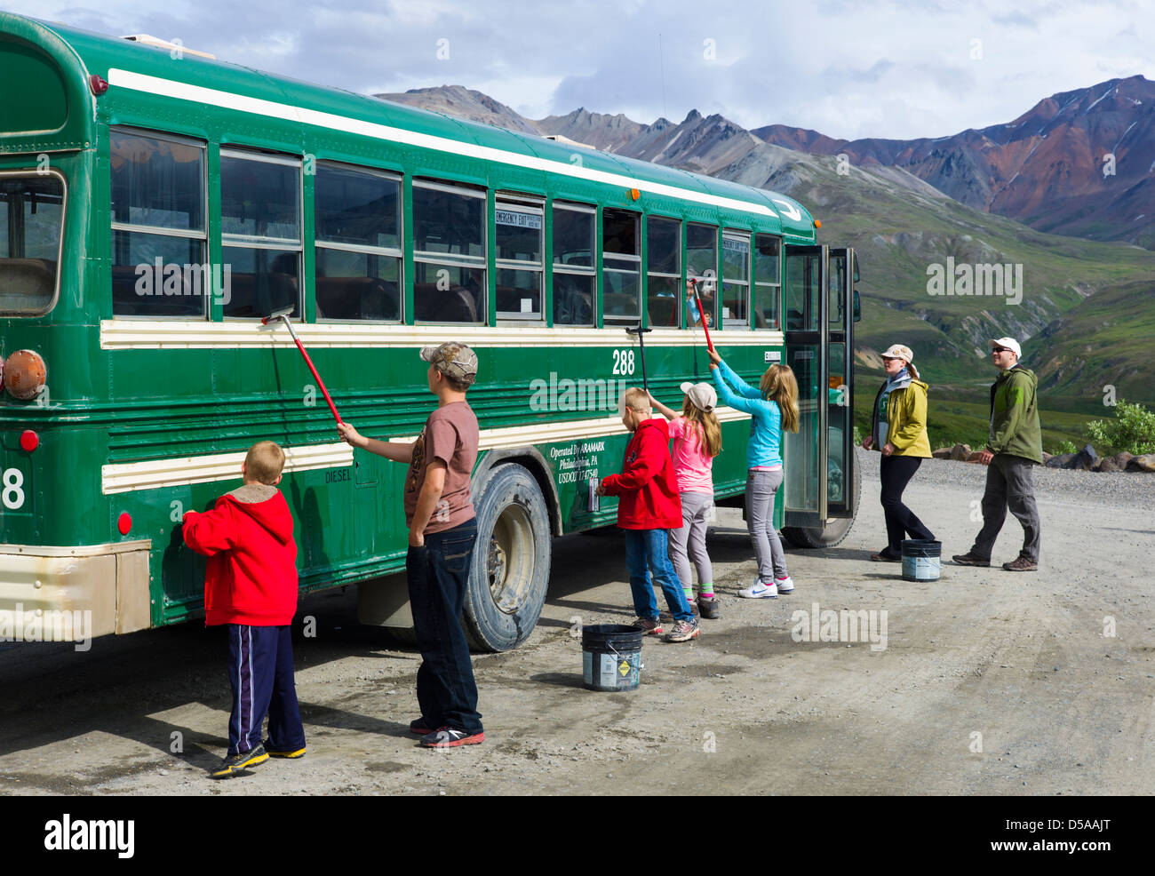 Young park visitors help clean the dust from the shuttle bus windows ...