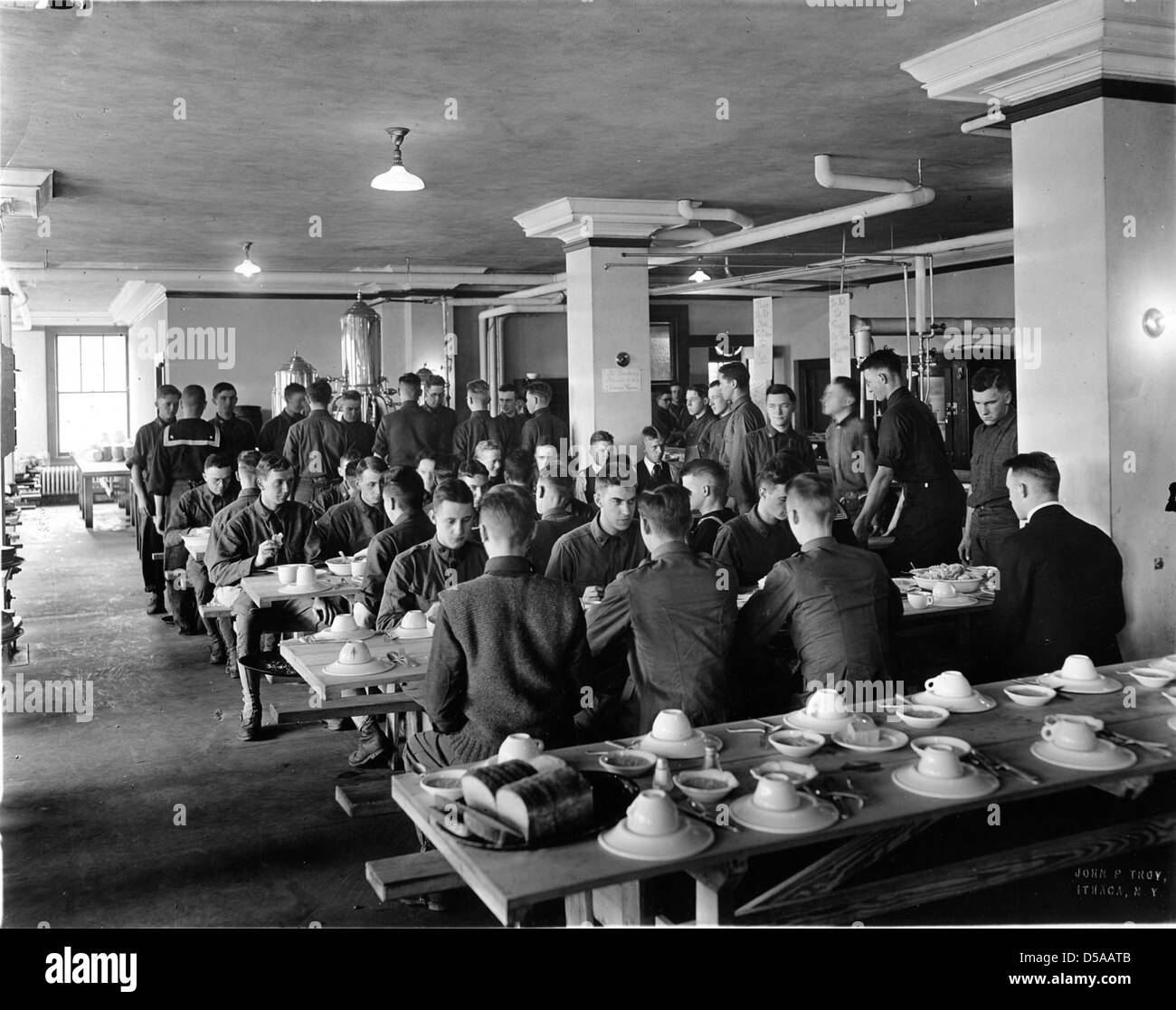 Assorted servicemen and one or two civilians eating in home economics ...