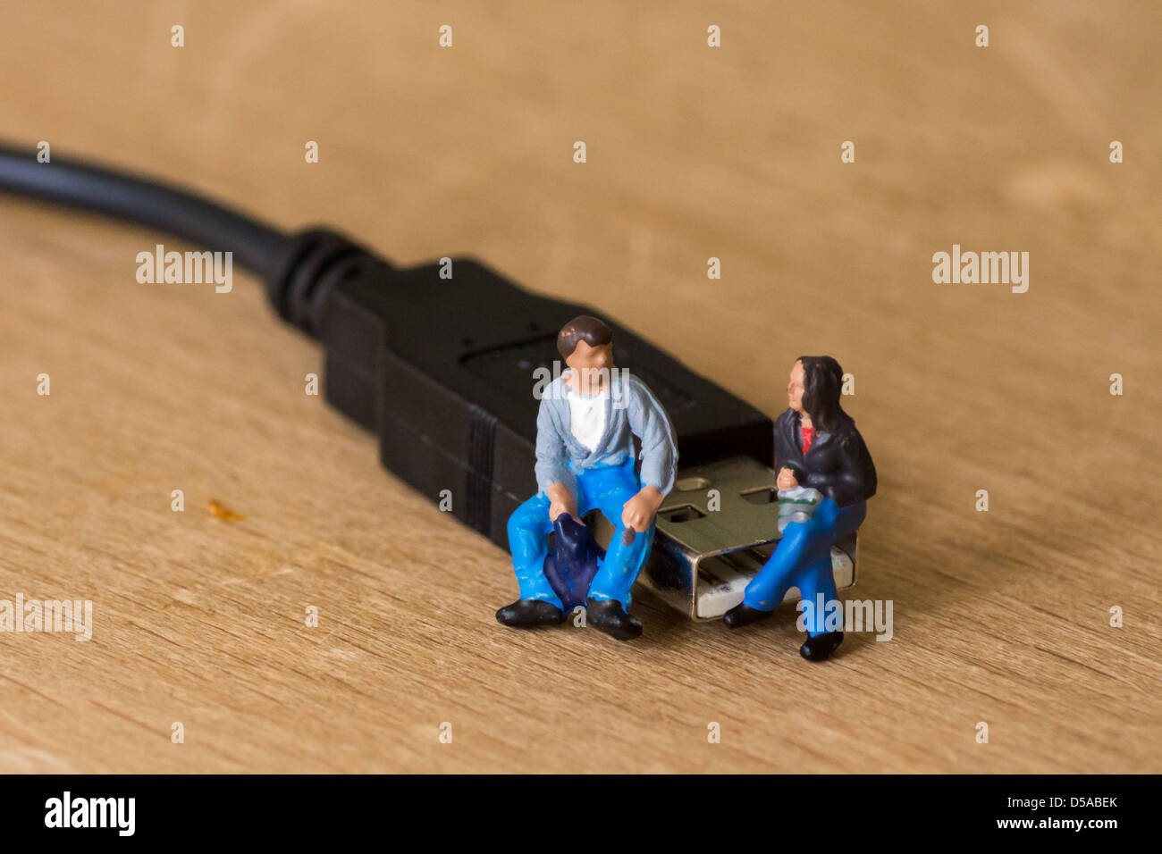 Little people chilling out sat on a USB cable Stock Photo - Alamy