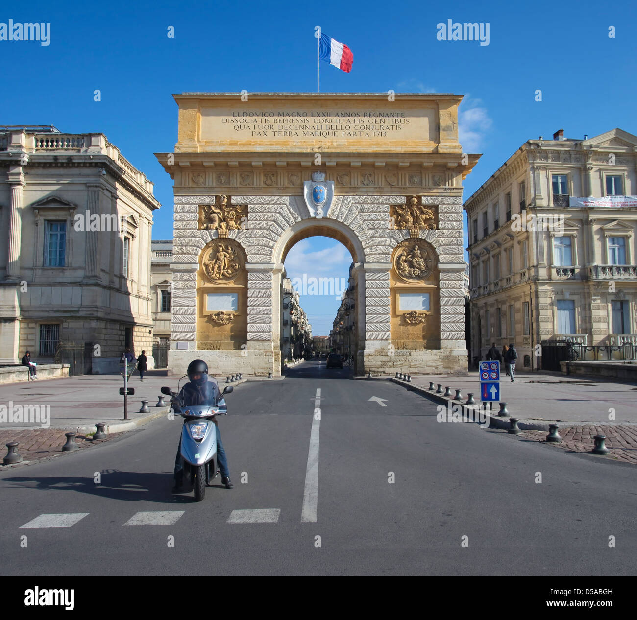 motorcyclist and pedestrians in front of grand archway in montpellier ...