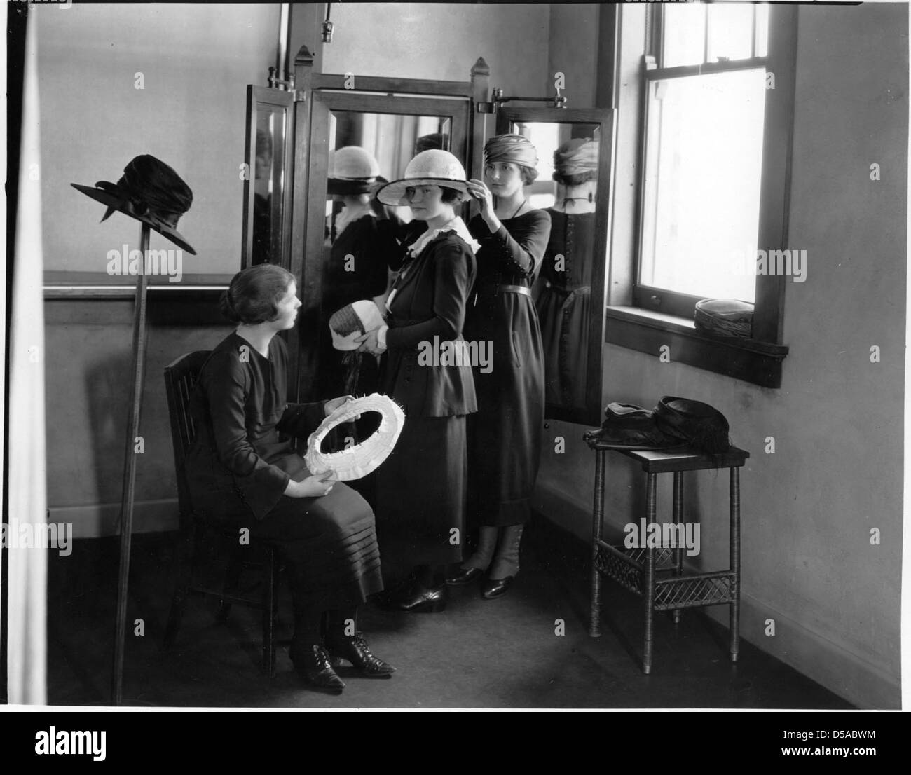 Students fitting millinery in class in home economics building about ...
