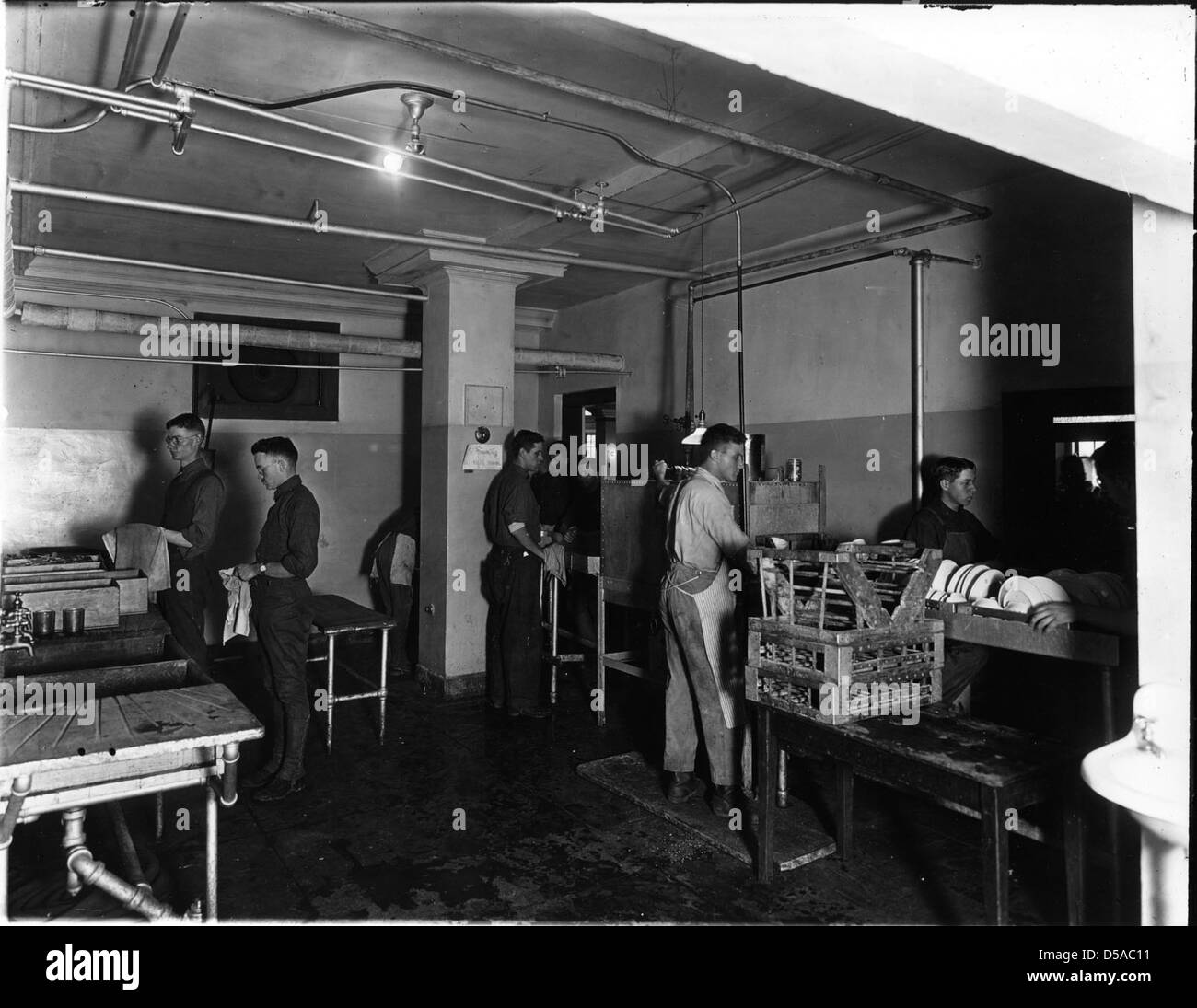This historical photograph shows servicemen in the dish room of a home ...