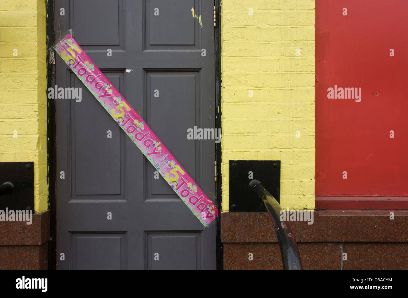 A child's fifth birthday banner has been pasted diagonally to the door ...