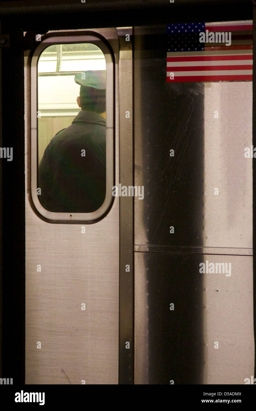 Back of an NYPD police officer seen through the window on an MTA subway ...