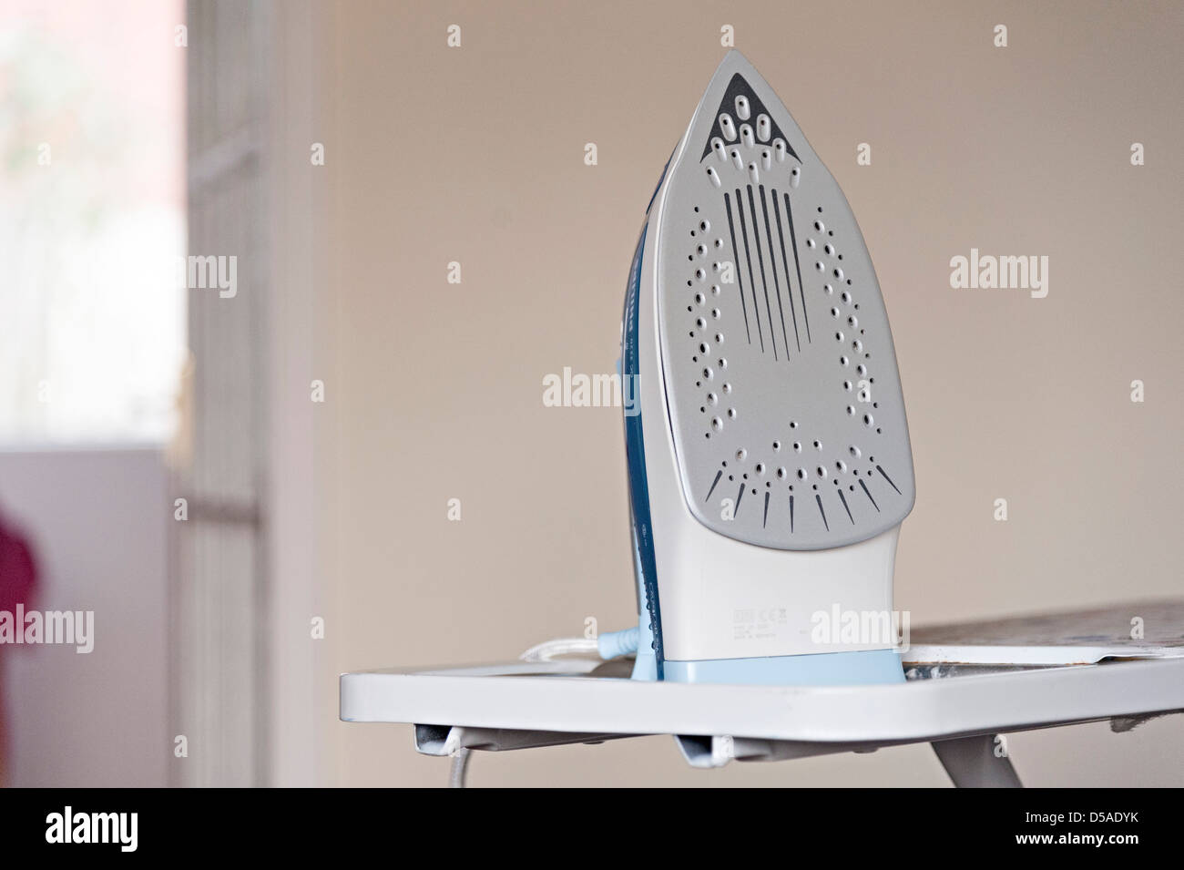 an iron sitting on an ironing board ready to iron a house holds clothes ...