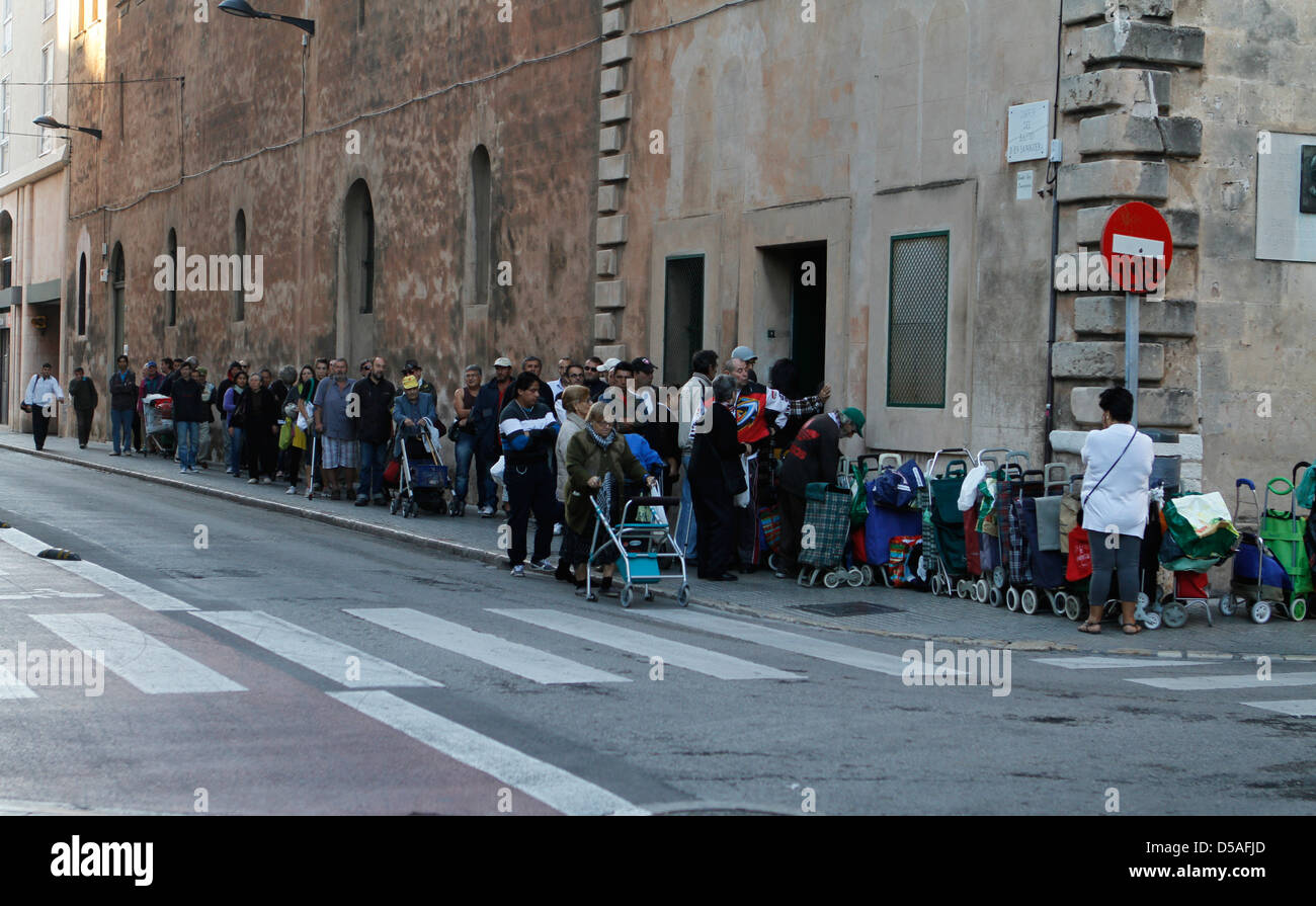 Dozens of people wait in a queue on a charity center to receive weekly ...