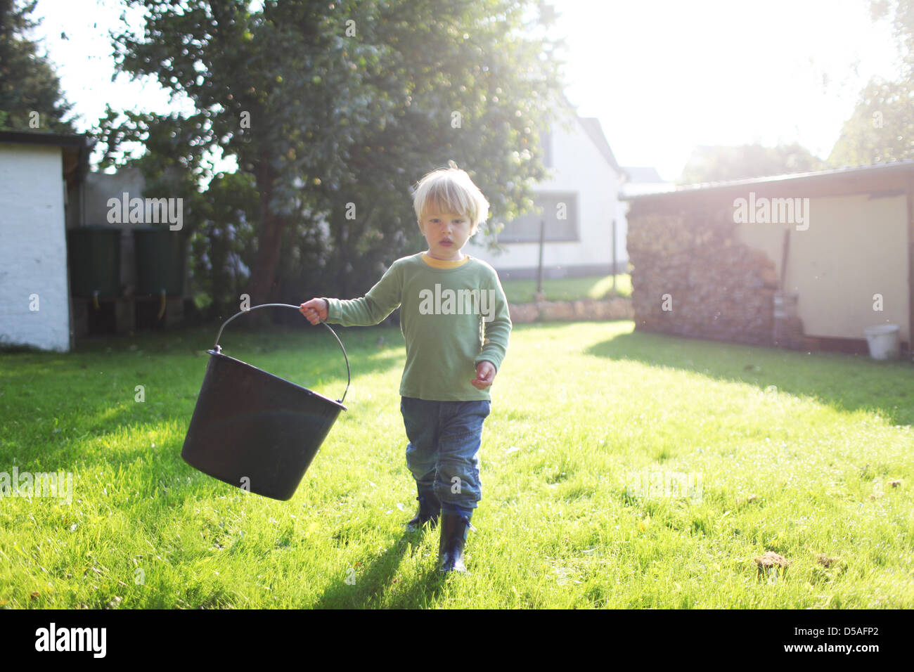 Handewitt, Germany, a boy with a bucket in hand in the garden Stock ...