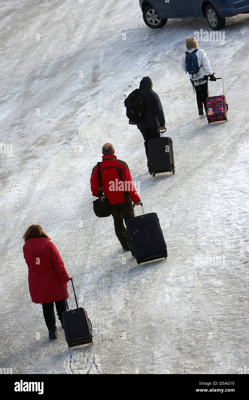 people pulling wheeled luggage walk across ice at kirkenes harbour ...