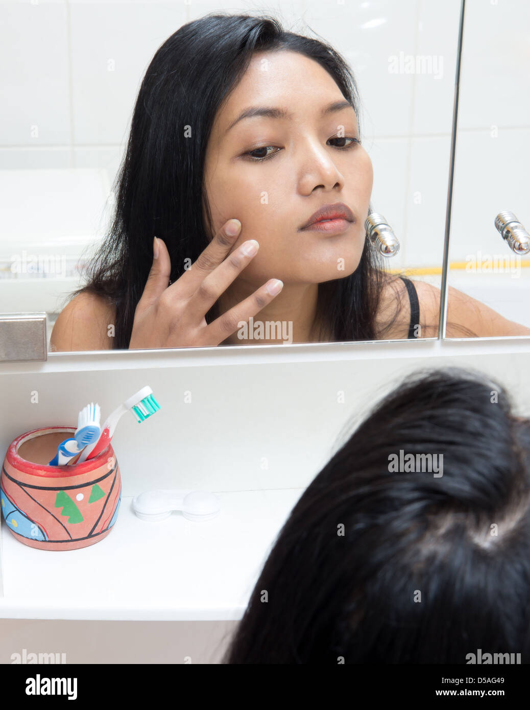 Woman looking at her reflection in the mirror Stock Photo - Alamy