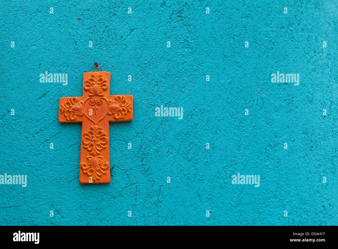 Terracotta cross on a turquoise wall of a traditional Mexican house ...
