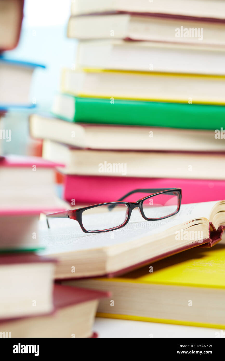 Vertical image of eyeglasses lying over opened book in the library ...