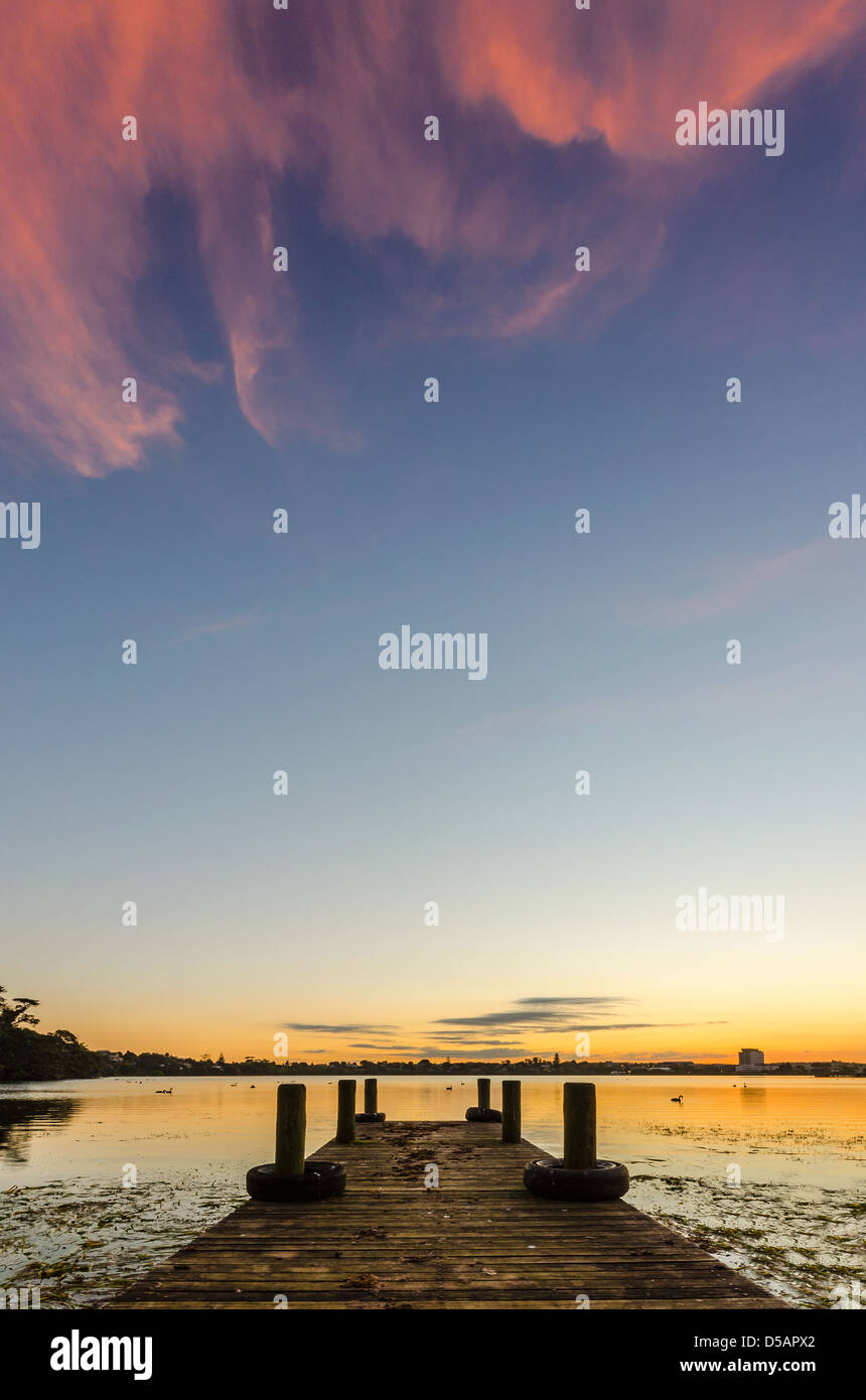 sunset over a lake looking out over a pier with colourful clouds from ...