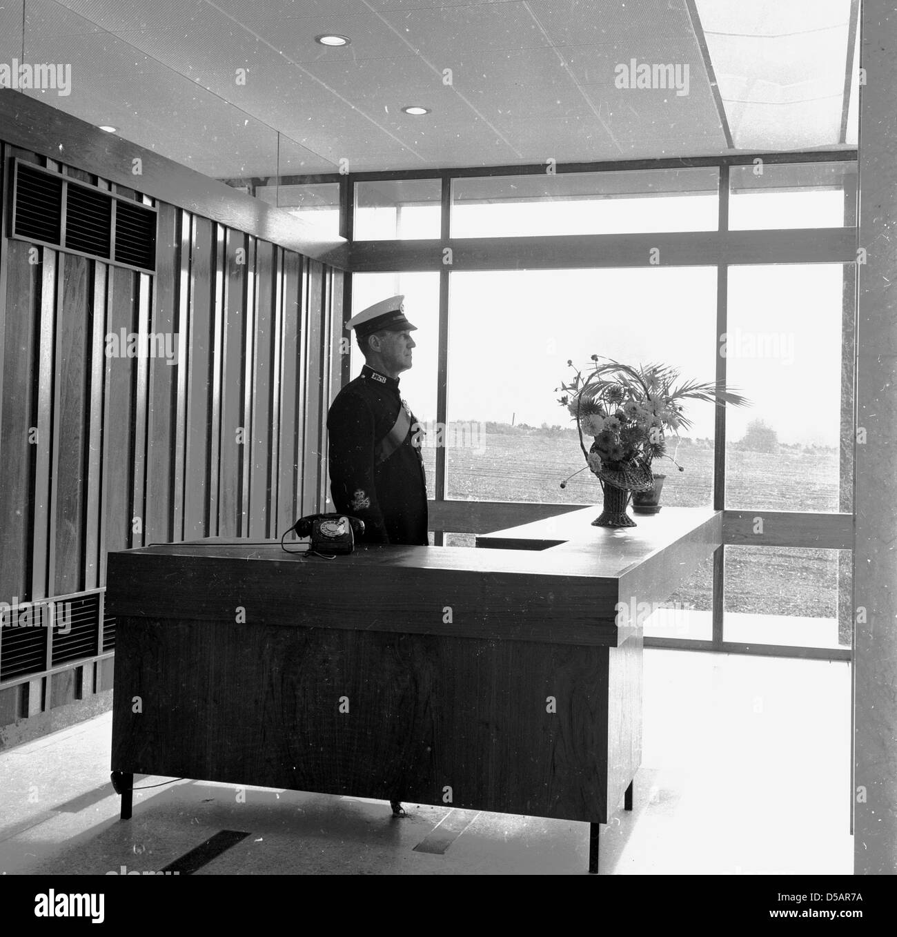 Historical picture from 1960s. Daytime and a uniformed security guard ...