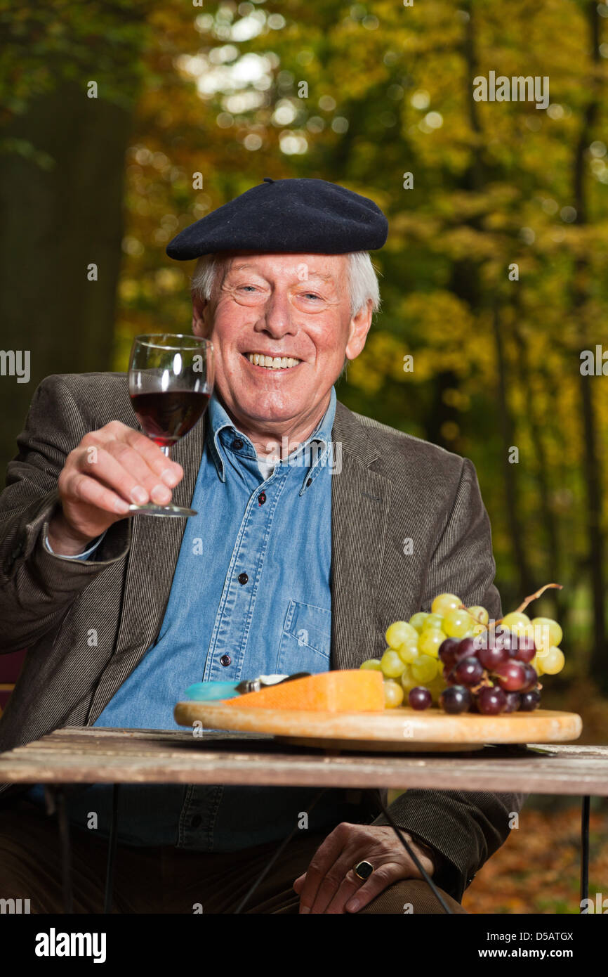 Senior french man enjoying red wine and cheese outdoors in autumn ...