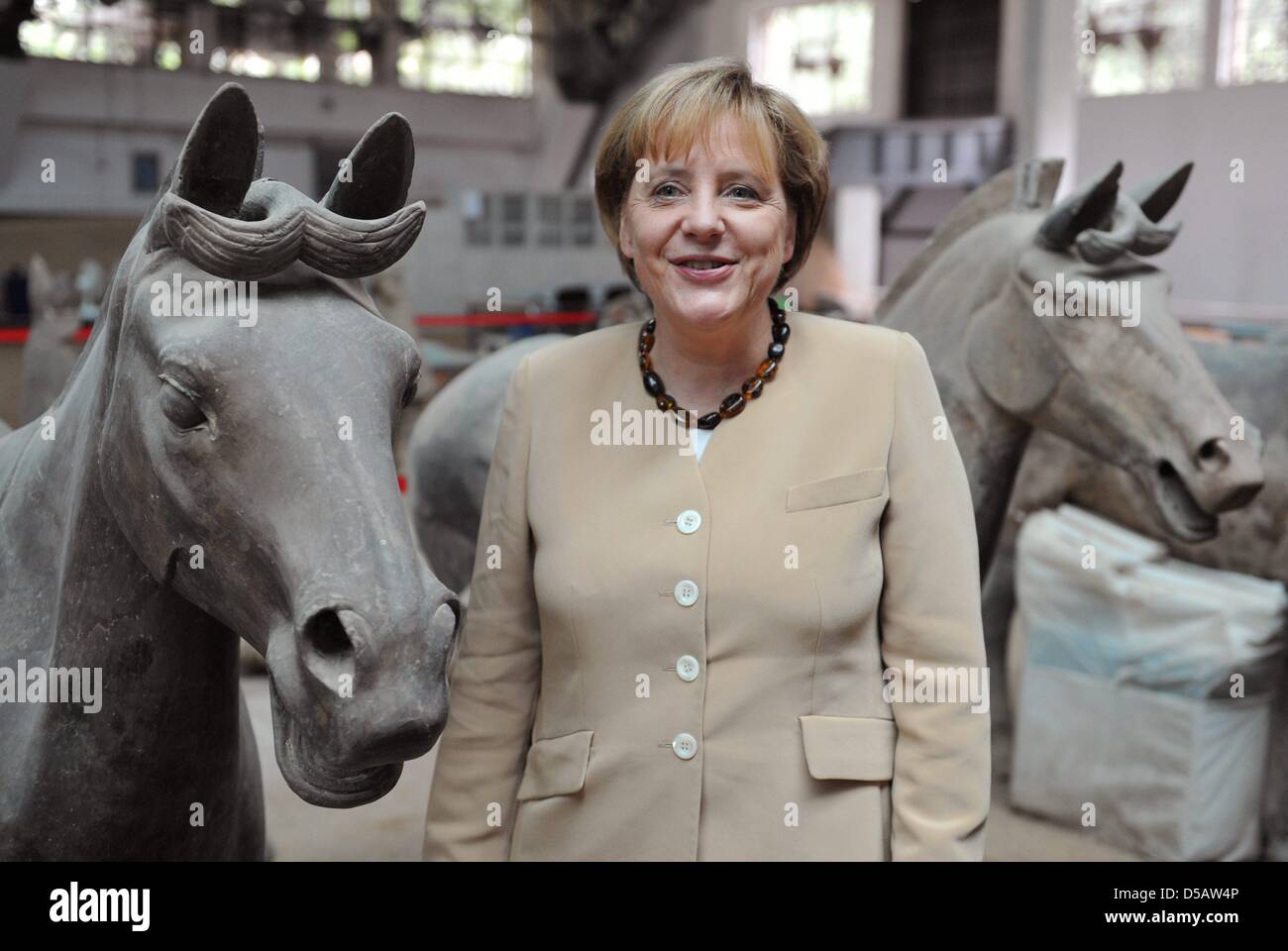 German Chancellor Angela Merkel smiles between two horses of the ...