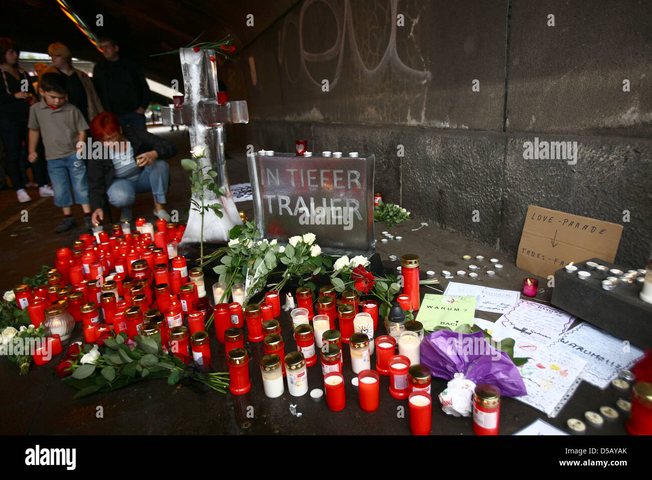 People mourn in the tunnel that formed the entrance to Love Parade ...