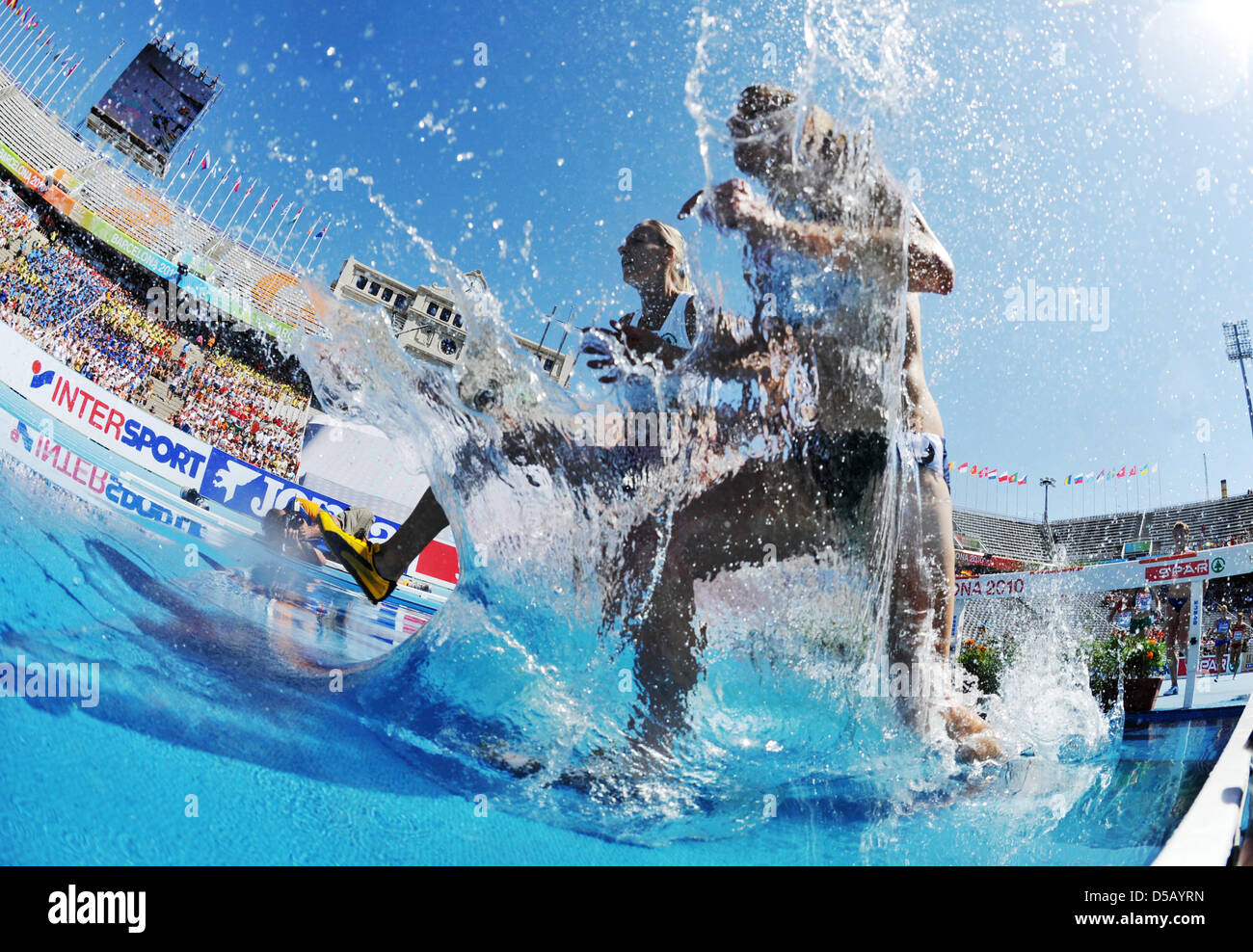 The picture features athletes as they run through a water basin at ...