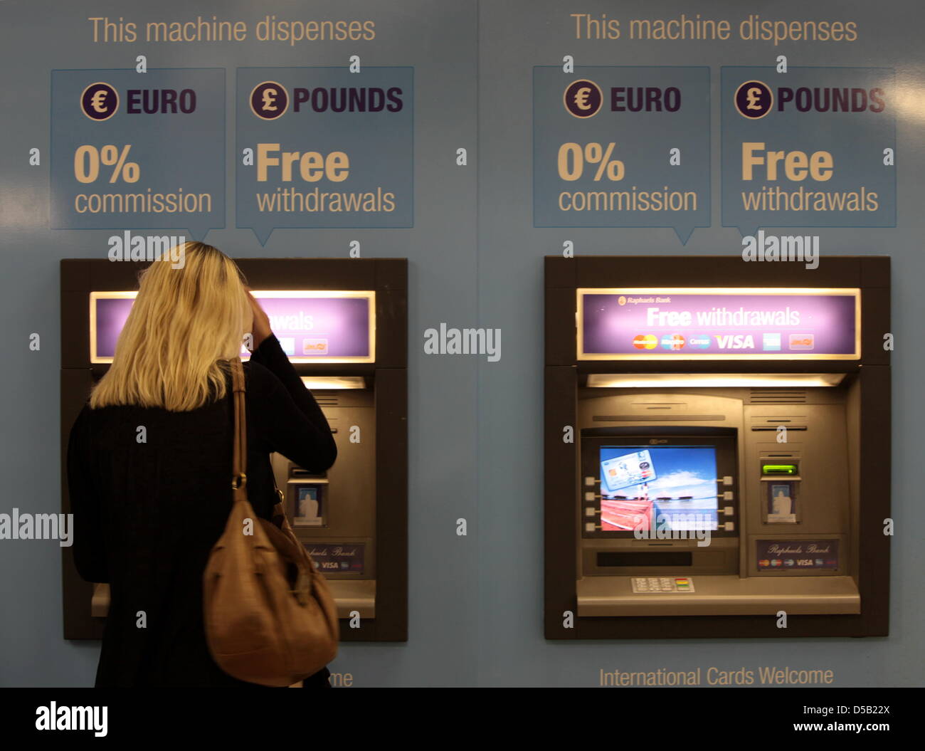 A woman stands at an automatic cash dispenser which gives out pounds as ...