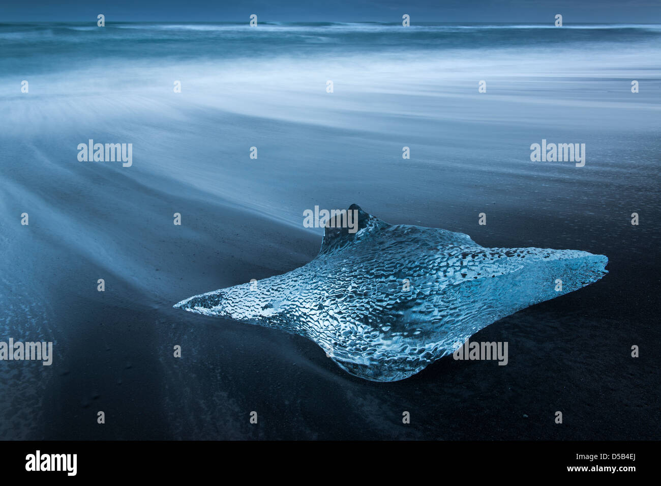 Stranded ice block washed ashore on a sand beach. Jökulsarlon glacier ...