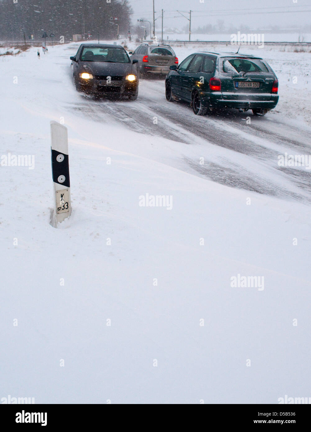 Cars drive through snowdrifts on a country road near Pillgram, Germany ...