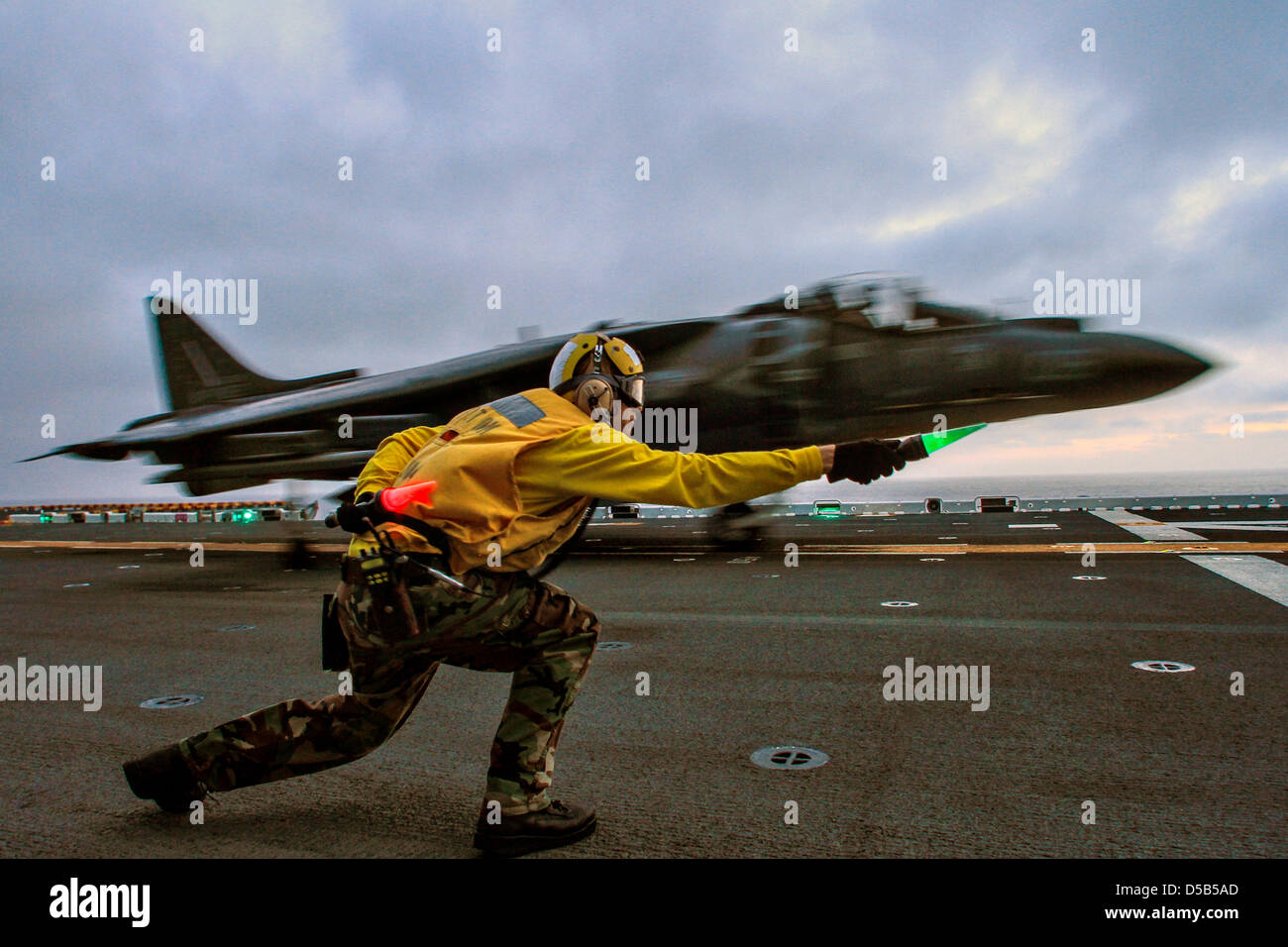A US Navy flight operations sailor clears a Marine Corps AV-8B Harrier ...