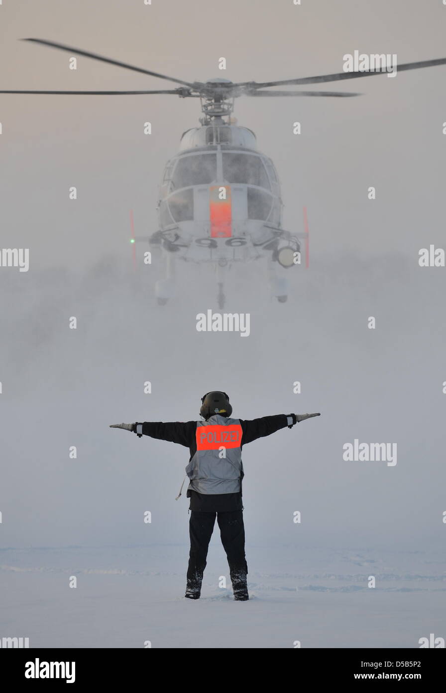 A policeman directs a landing helicopter at the site of a crashed ...