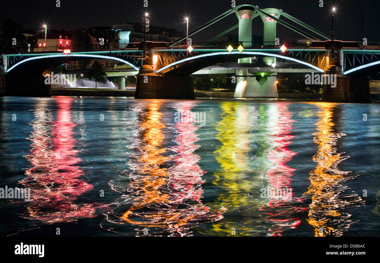 The illuminated Ignatz Bubis bridge mirrors in the waters of Main river ...