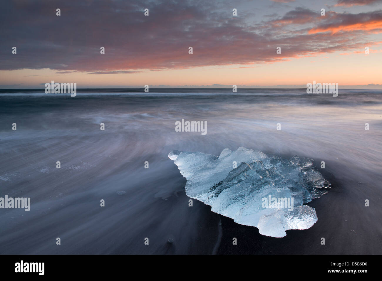 Stranded ice block washed ashore on a sand beach. Jökulsarlon glacier ...
