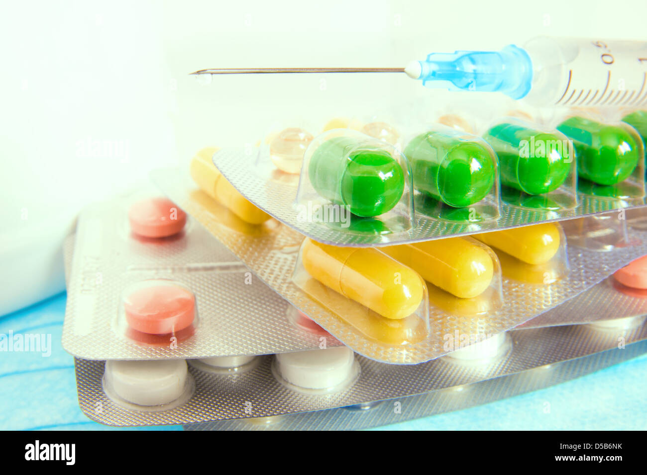 Stack of colorful pills and syringe on medical table. Cutout ...