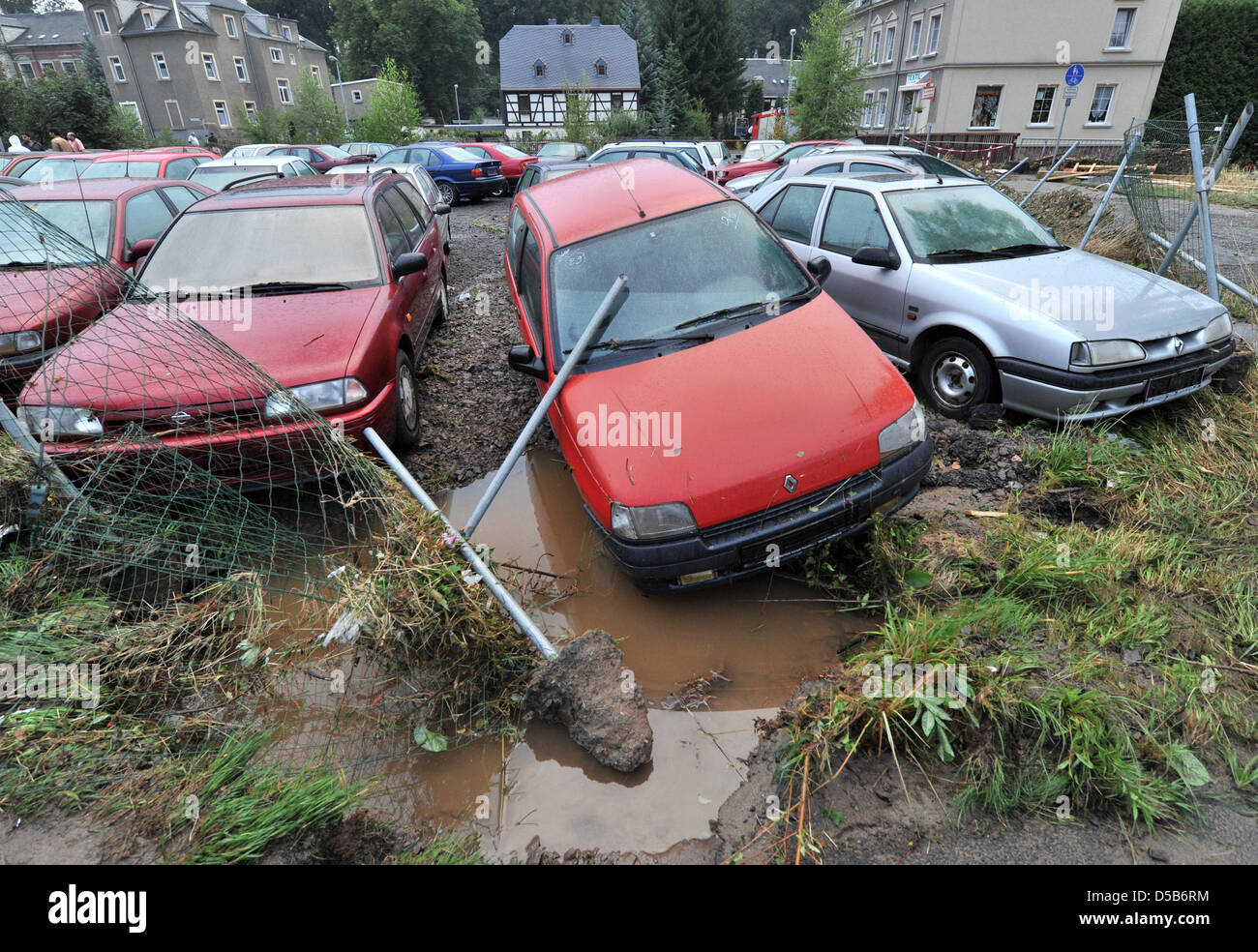 Damaged cars line the parking lot of a used car dealership after heavy ...