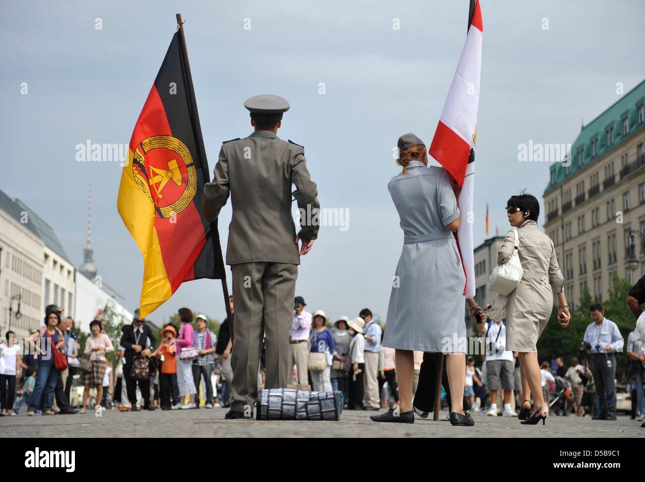 A man clad in an East German army uniform poses with a GDR flag next to ...